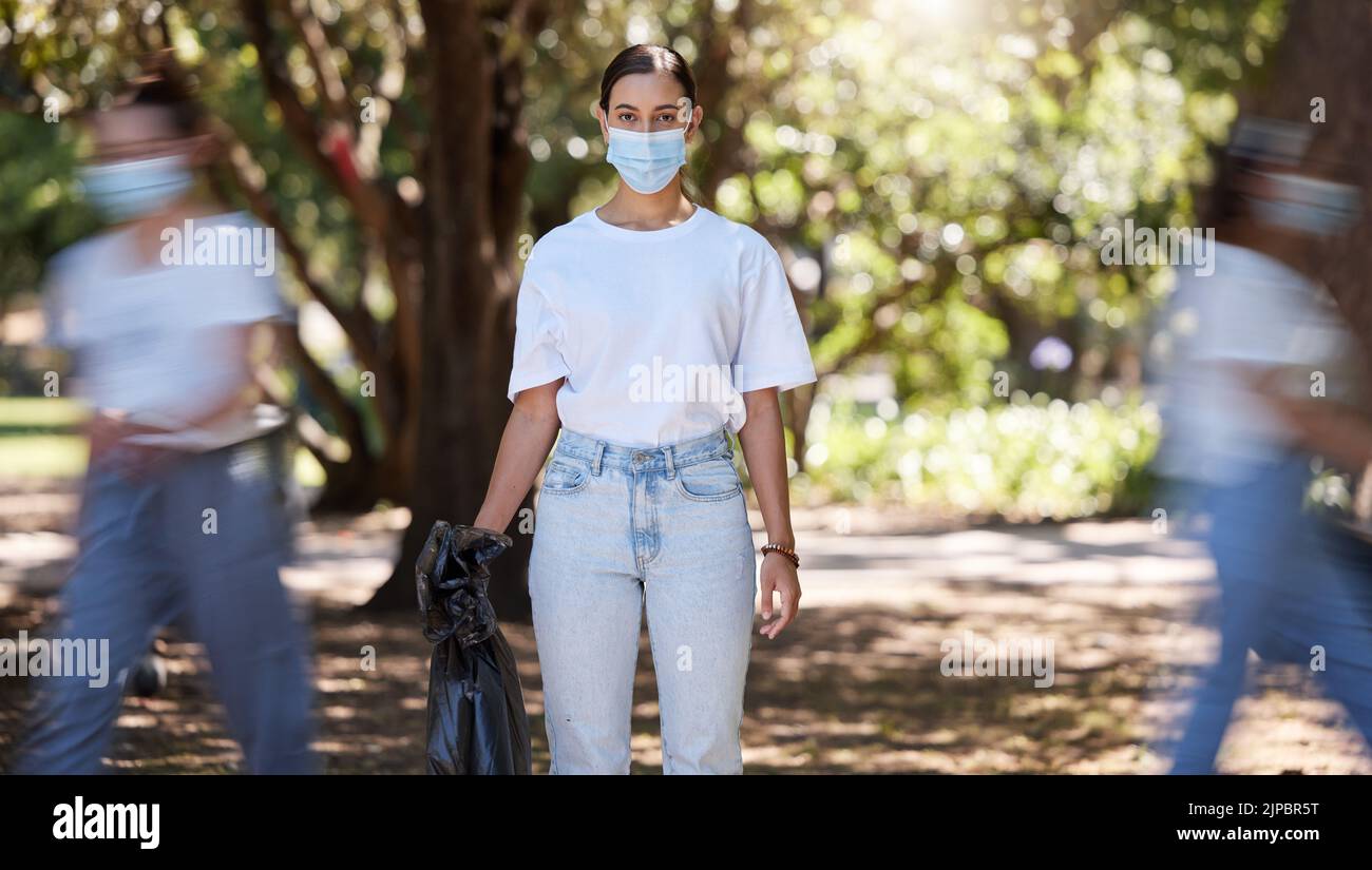 Female wearing covid mask cleaning the park for a clean, hygiene and ...