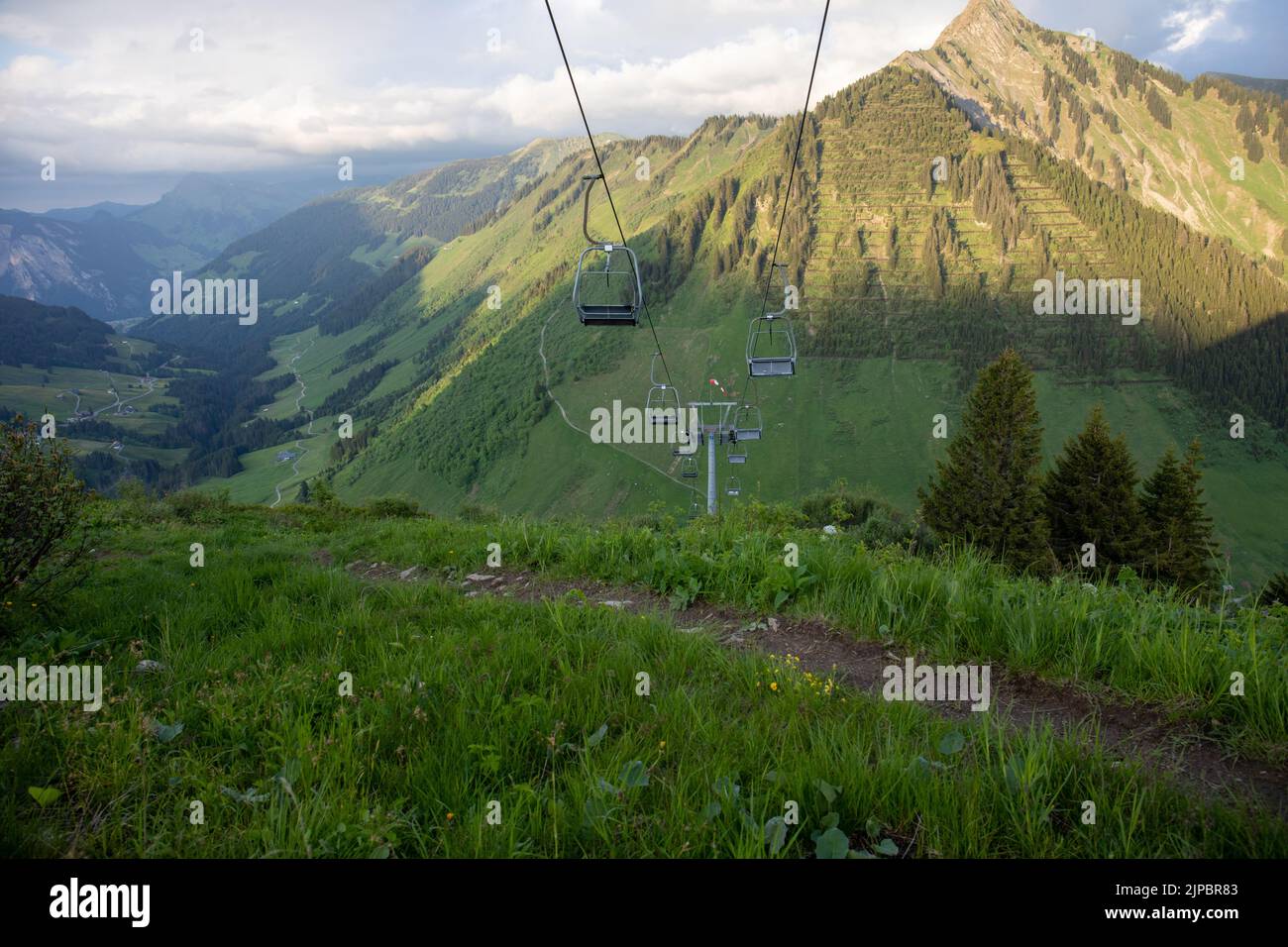The telecabin passing over the green slopes on a sunny day in the ...