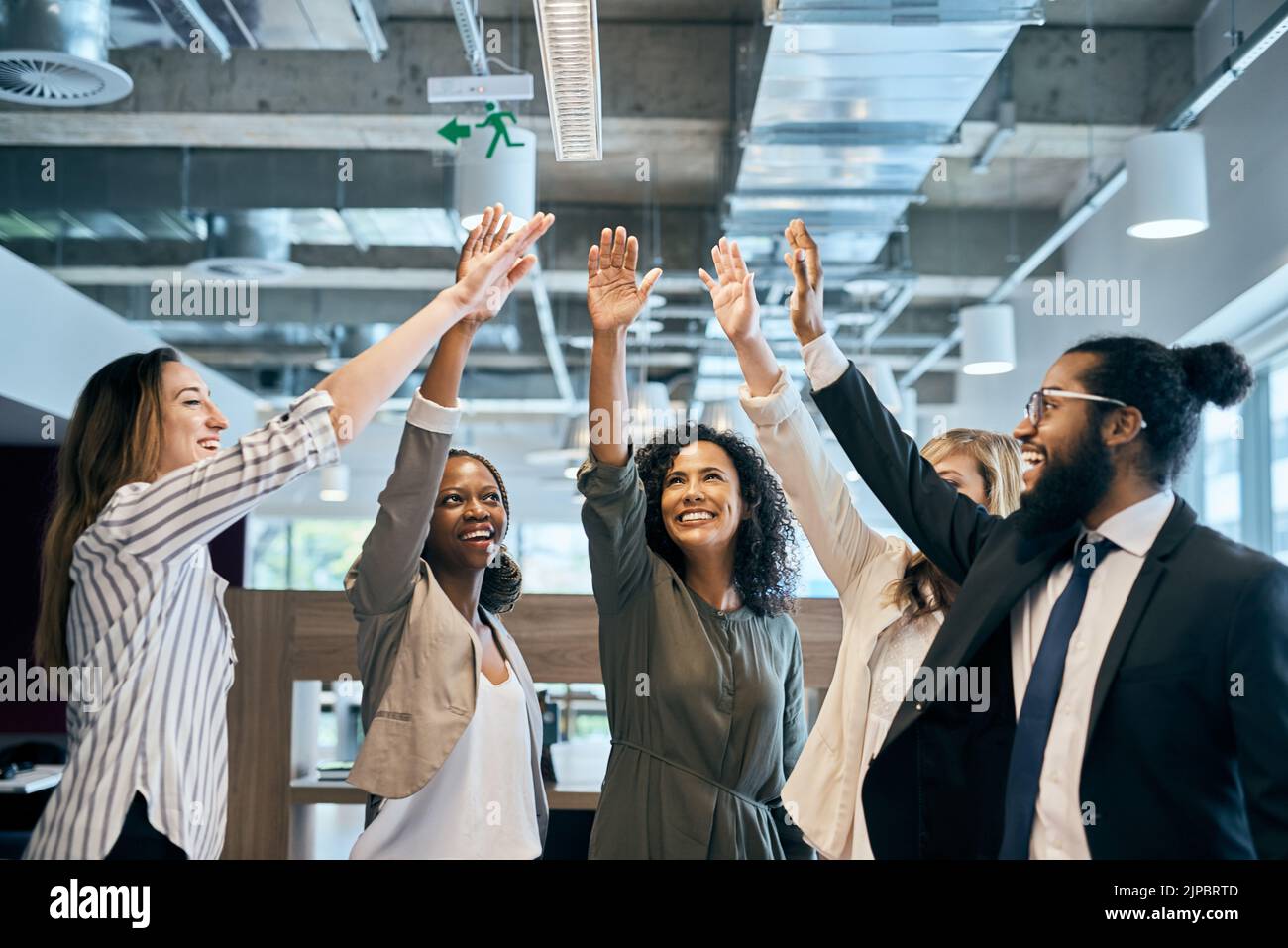 Lets put them up team. a group of cheerful young businesspeople stretching out their hands for a ...