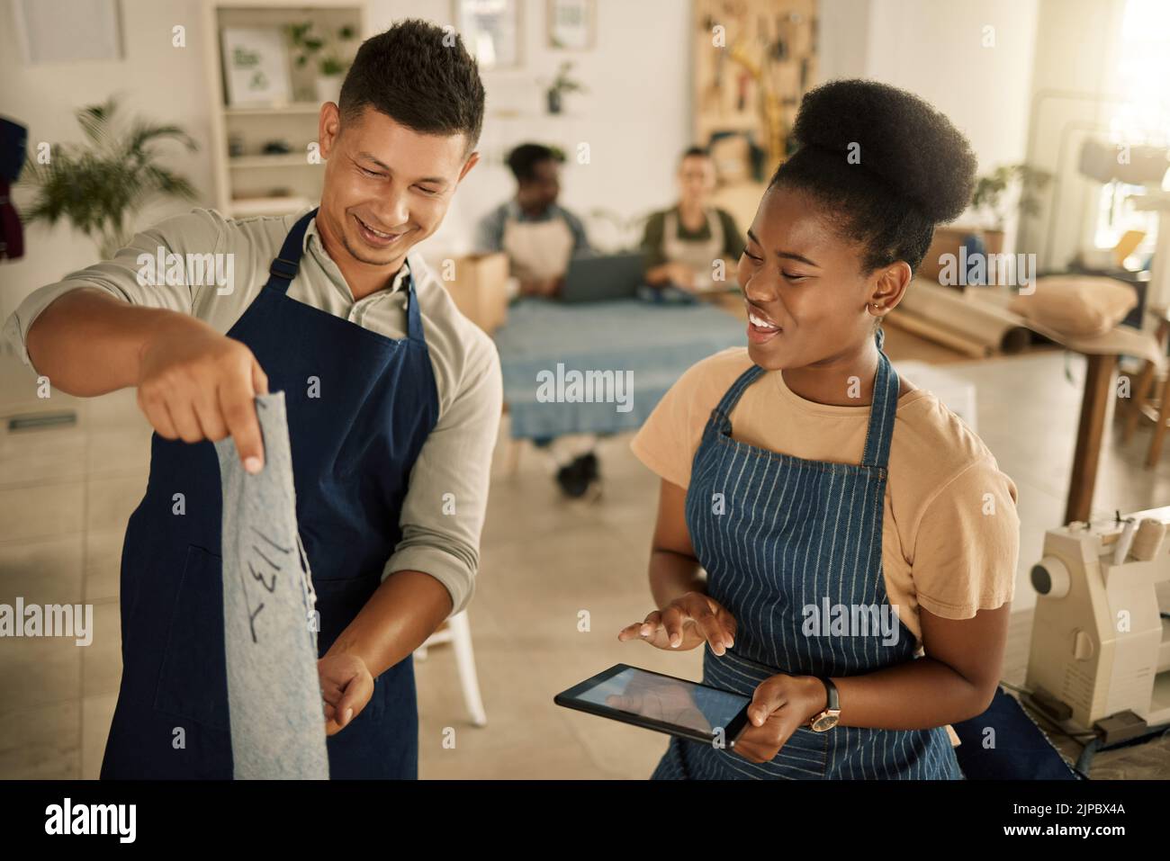 Tailor, seamstress and dressmaker talking with a colleague in a modern ...