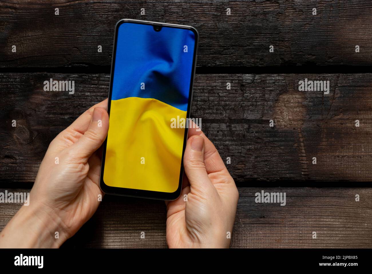The national flag of Ukraine as a background on the phone in the hands ...