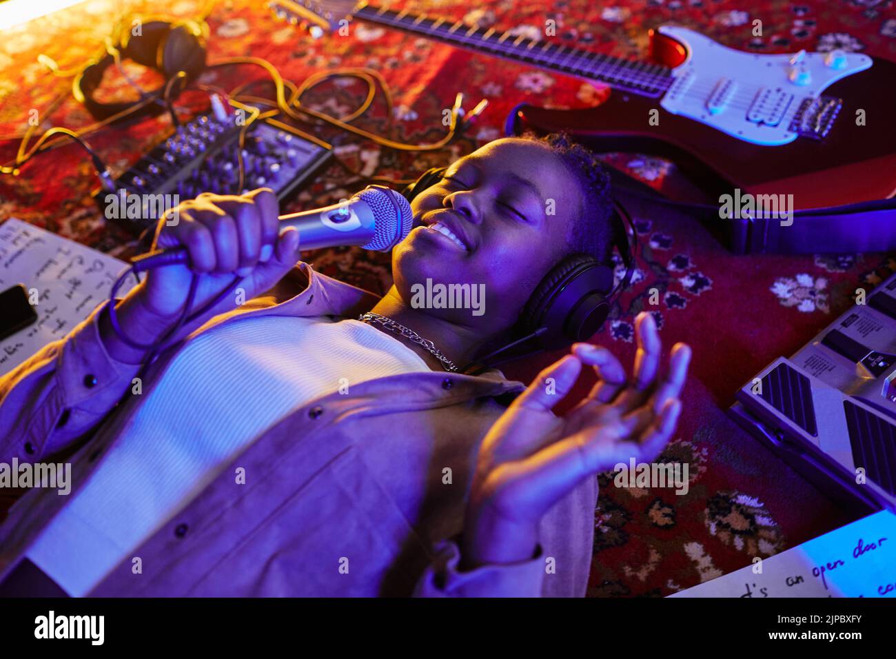 Closeup of smiling black woman holding microphone and singing lying on ...