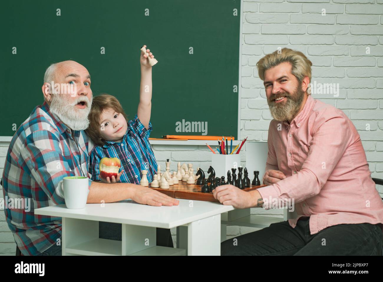 Grandfather father and son playing chess, happy men generations family ...