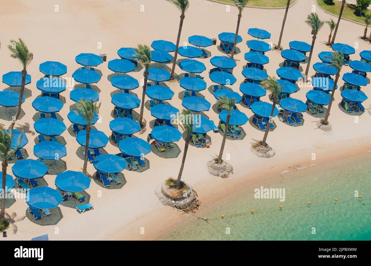 Aerial view above tropical beach in luxury hotel with umbrella parasols ...