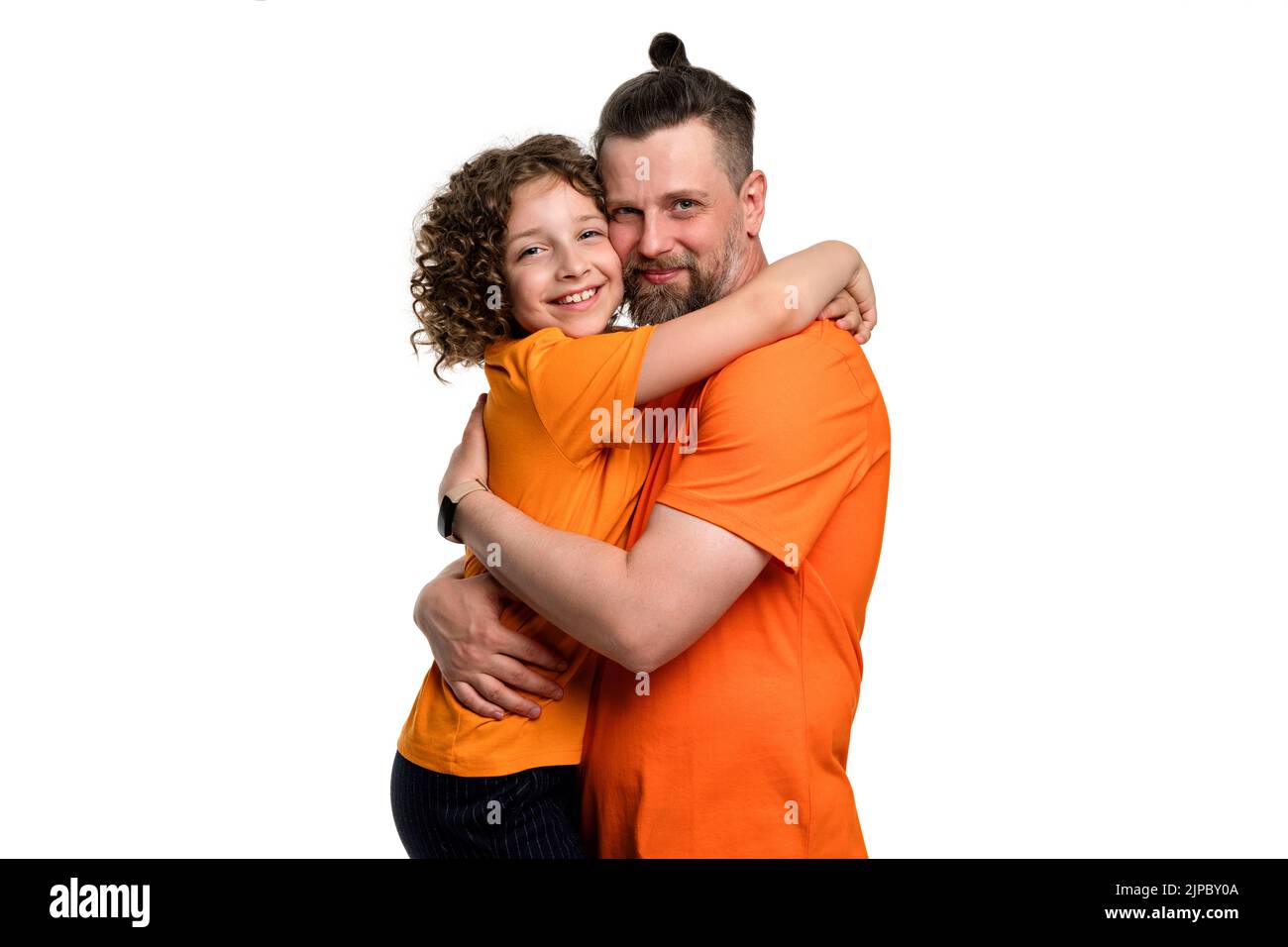 Cute curly short-haired girl 10-12s lovingly hugs handsome bearded dad ...