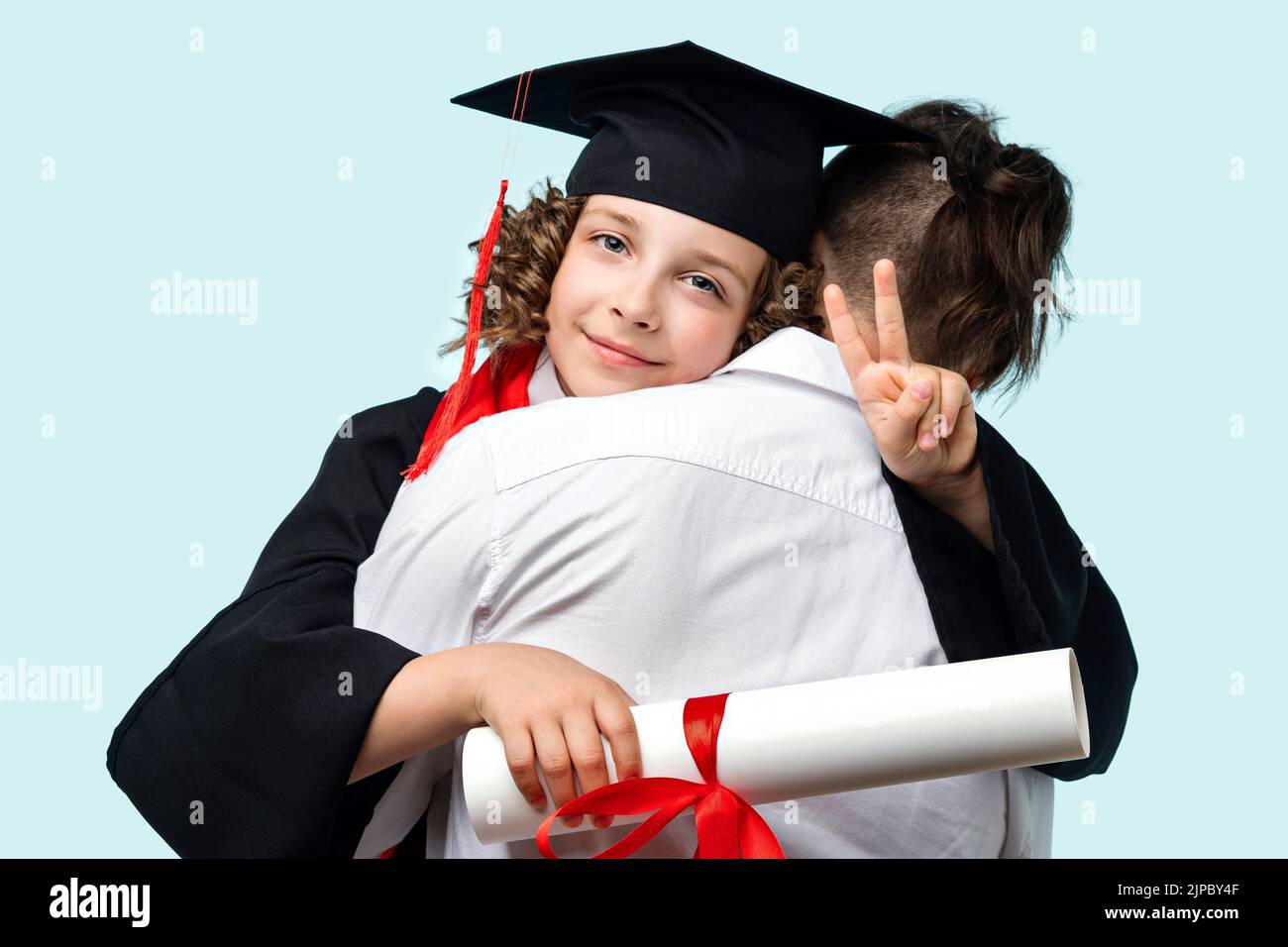 Child in graduation cap and ceremony robe holding diploma certificate ...
