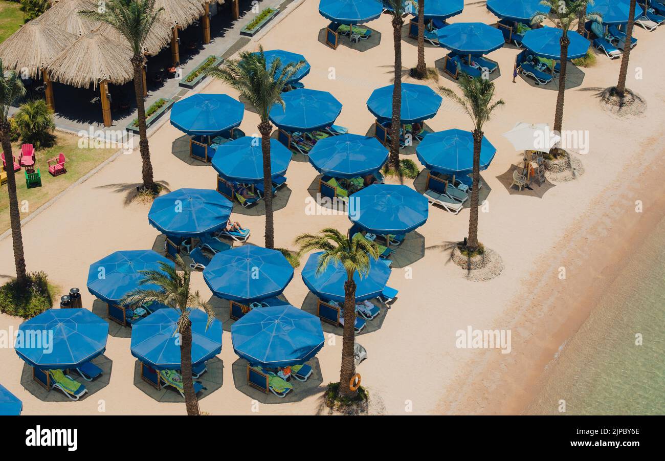 Aerial view above tropical beach in luxury hotel with umbrella parasols ...