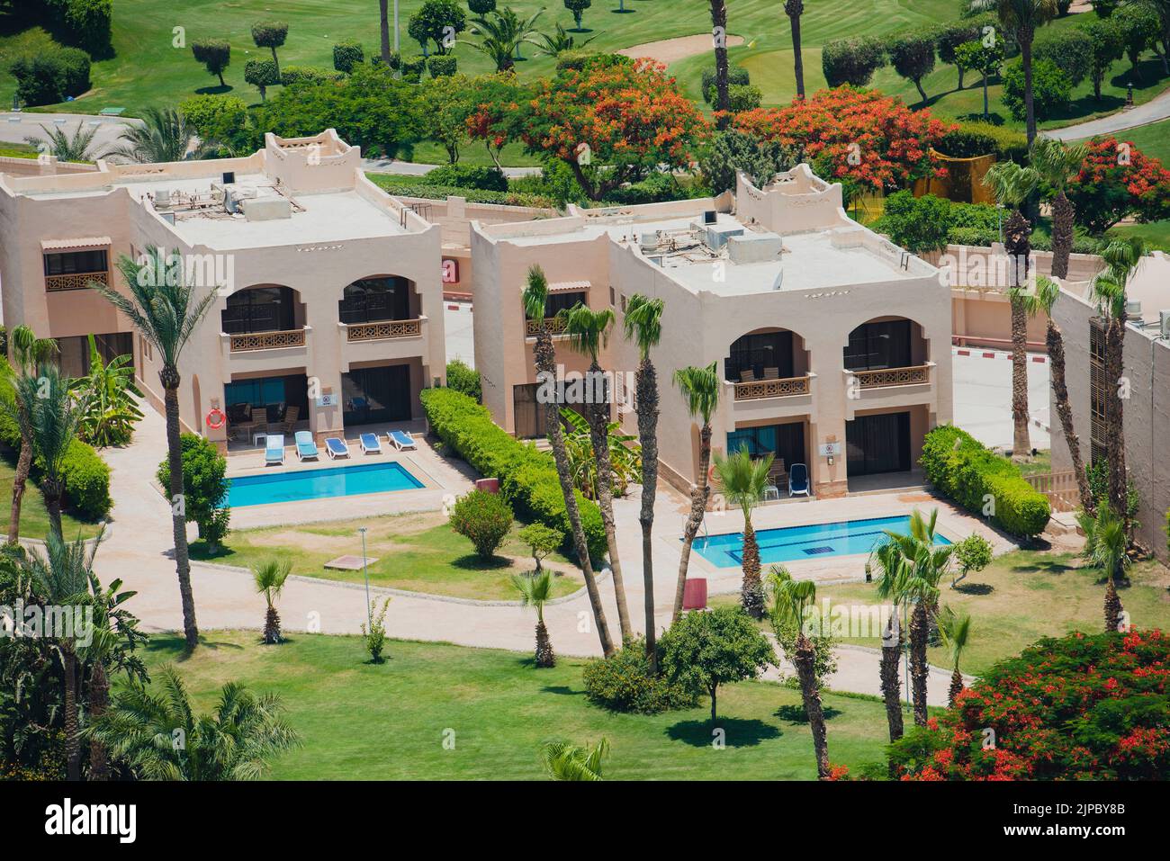 Aerial view over holiday villas with swimming pool in luxury tropical ...