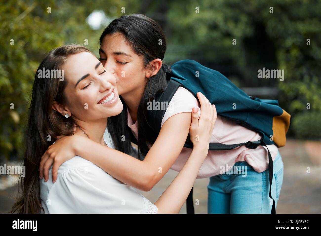 Daughter, hugging and giving a kiss to her mom before going into school ...