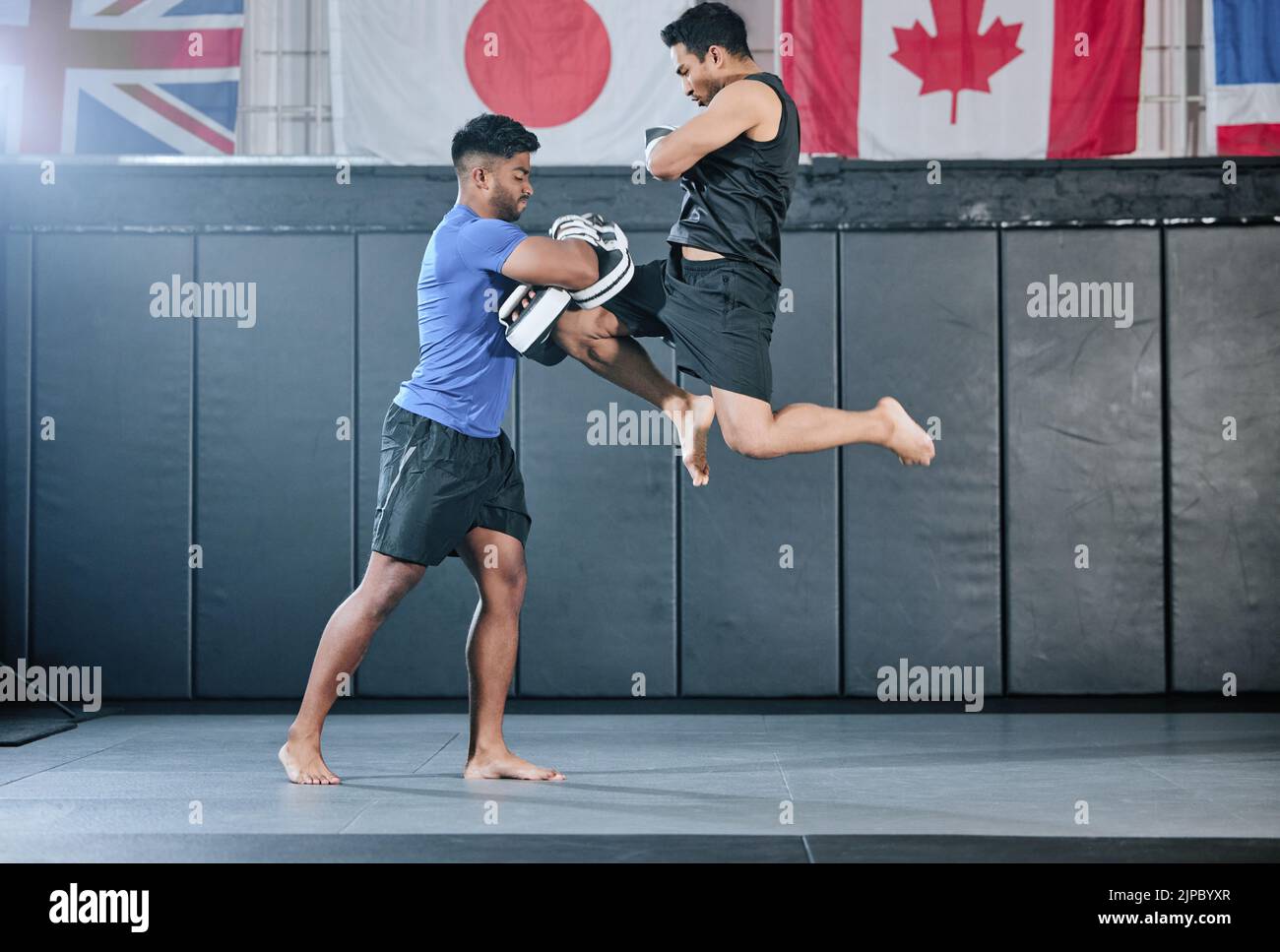 Healthy professional coach sparring and training male kickboxer indoors ...