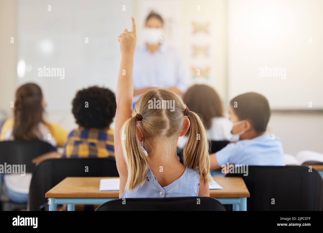 Learning, smart and little girl in class holding up a hand to answer a ...