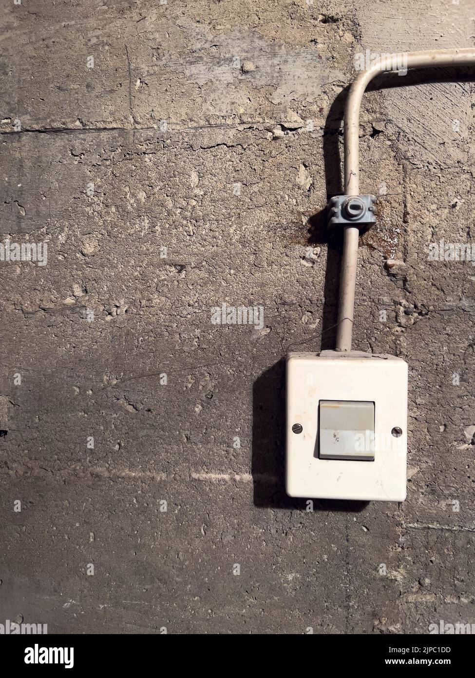 The vertical close-up view of an old light switch on the concrete wall ...