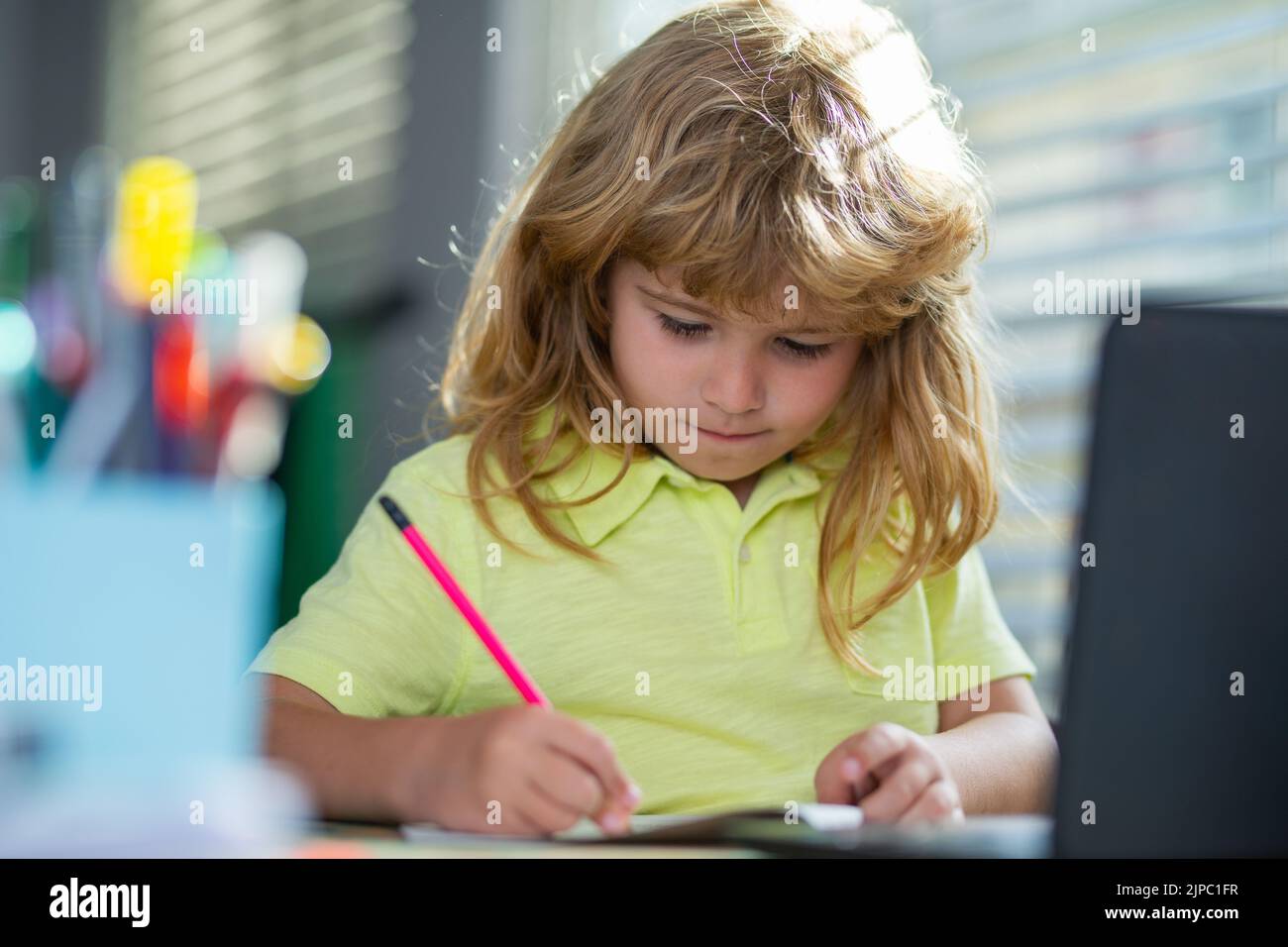 Serious school child writing homework in school class. Portrait of ...