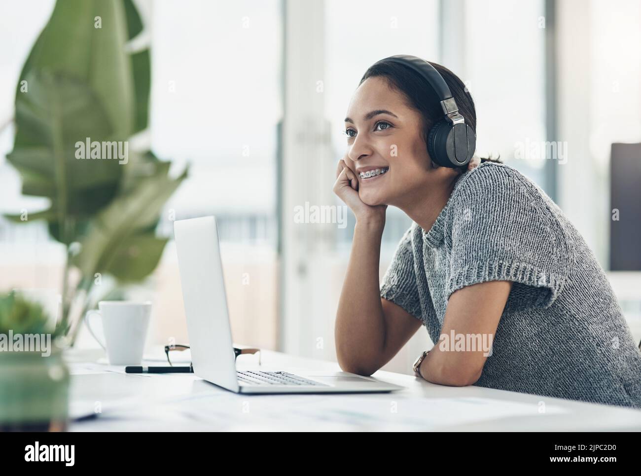 Happy, smiling business woman day dreaming of success at her office ...