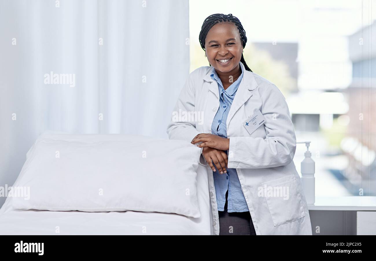 Happy doctor leaning on a hospital bed smiling, standing and ready to ...