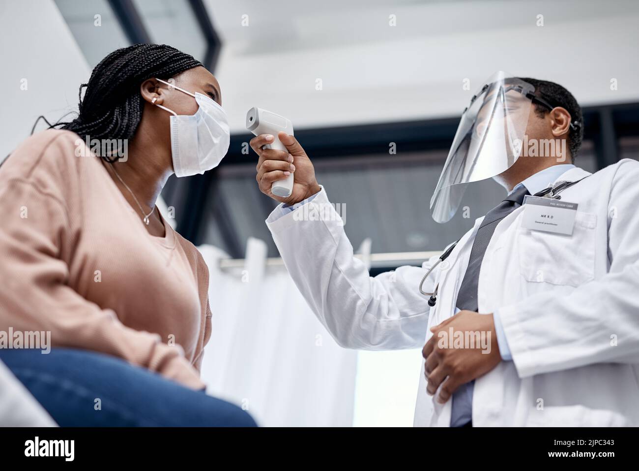 Covid screening with a doctor measuring temperature of a patient using ...