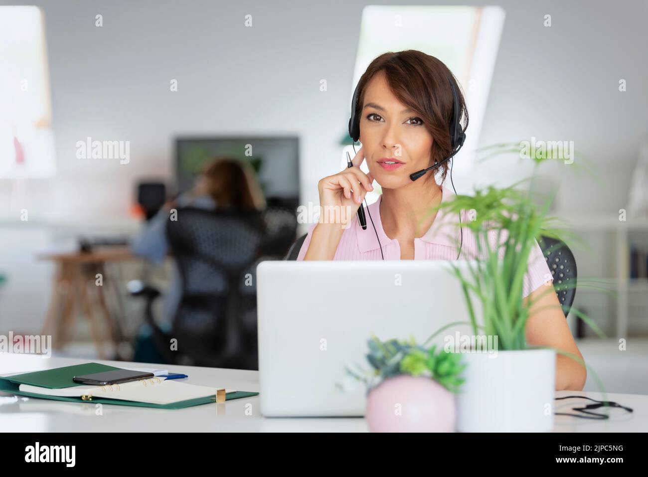 Customer service assistant wearing headset while sitting behind her ...