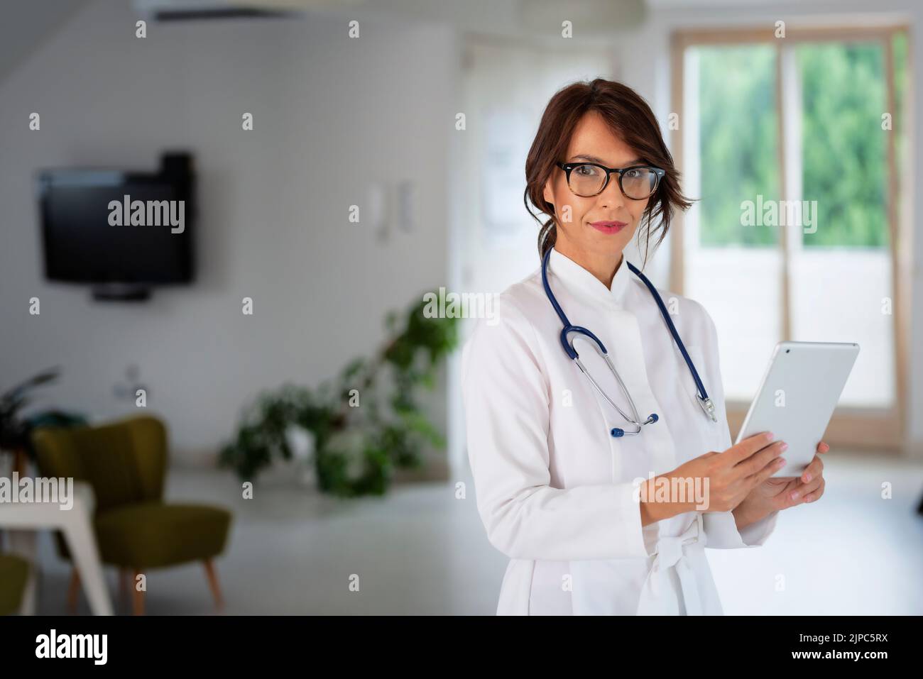 Portrait of a female doctor holding her patient chart on digital tablet ...