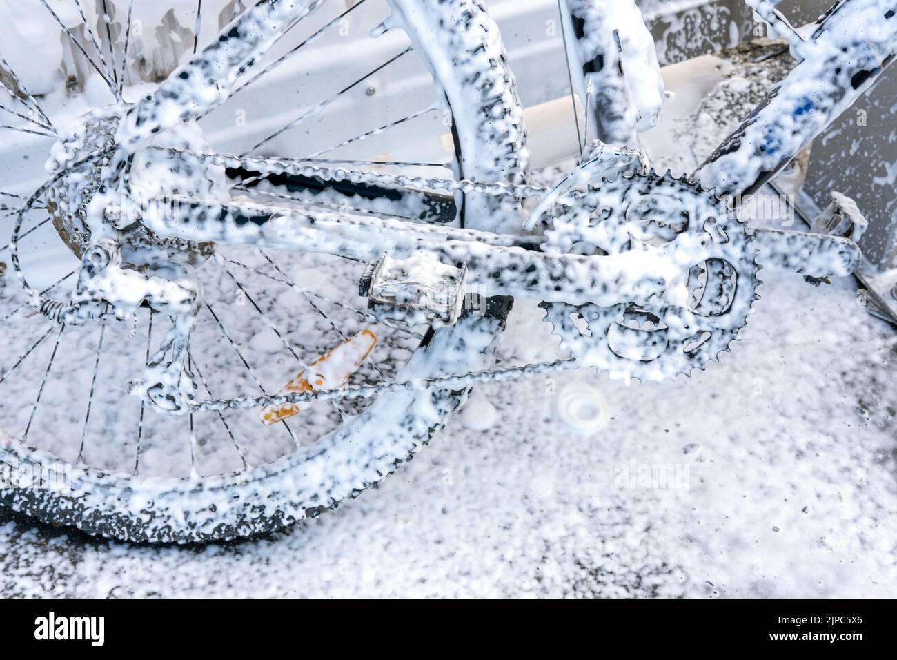 Washing a bicycle with a foam jet at a car wash. The bike is covered ...