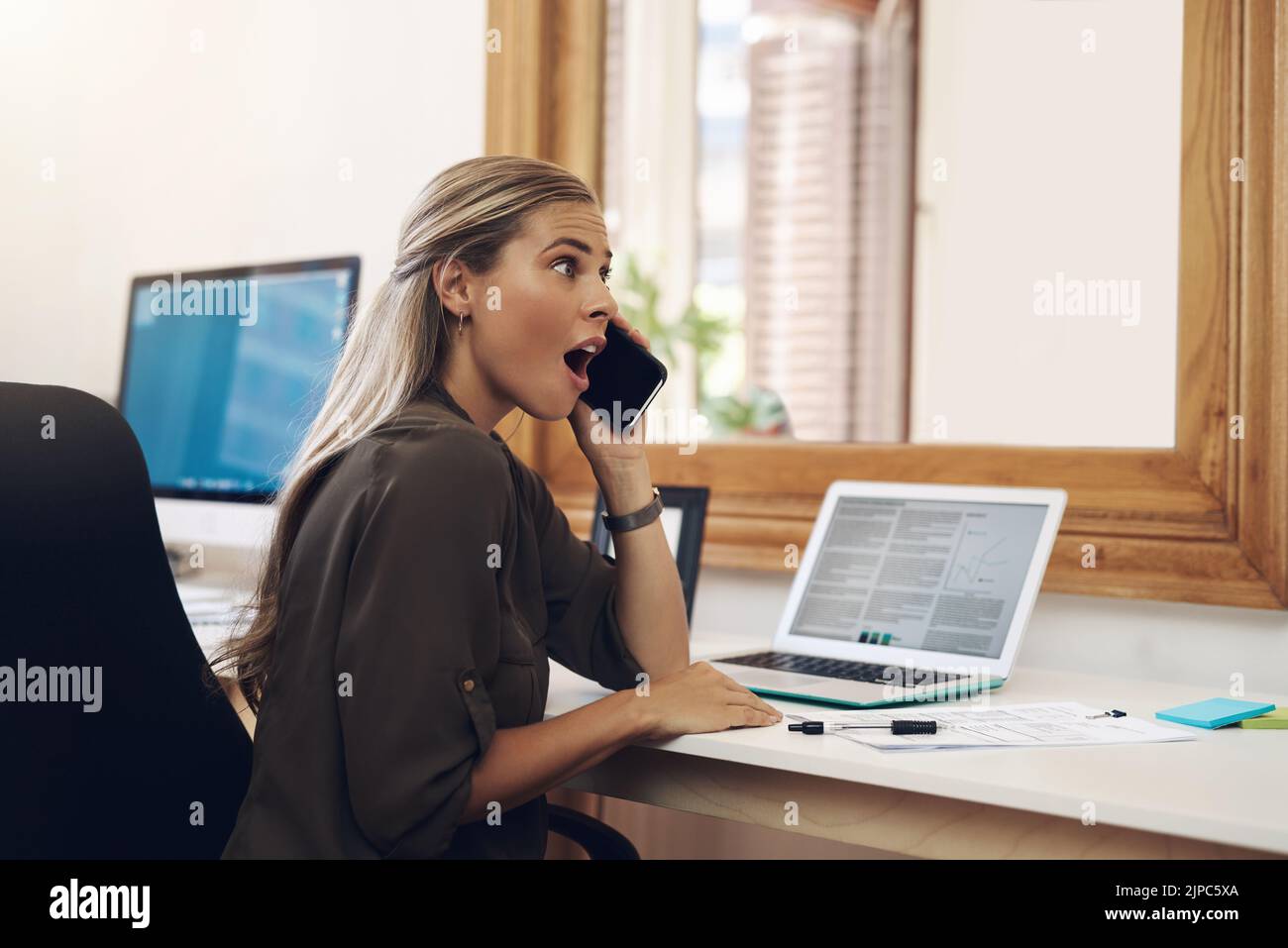 Surprised, shocked and excited young businesswoman gossiping and ...