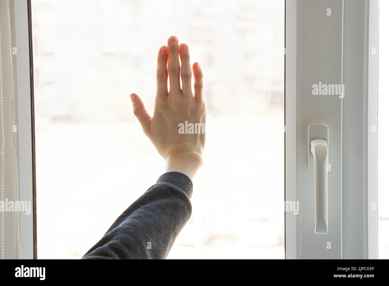 Women's hands on the window of the house in the sunlight during the day ...