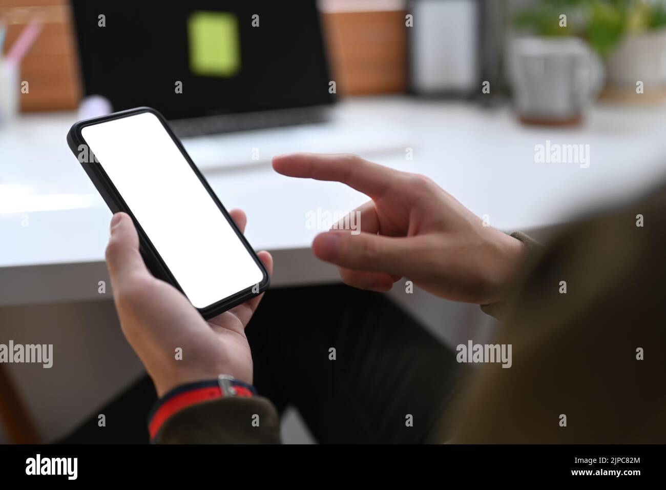 Close up view man sitting in his home office and using mobile phone ...