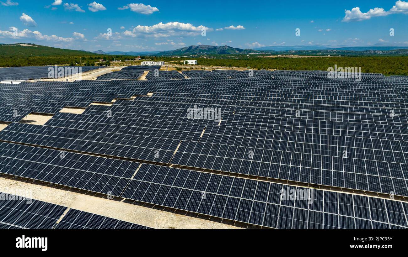 Aerial view low over a photovoltaic energy farm, built on sand, in ...