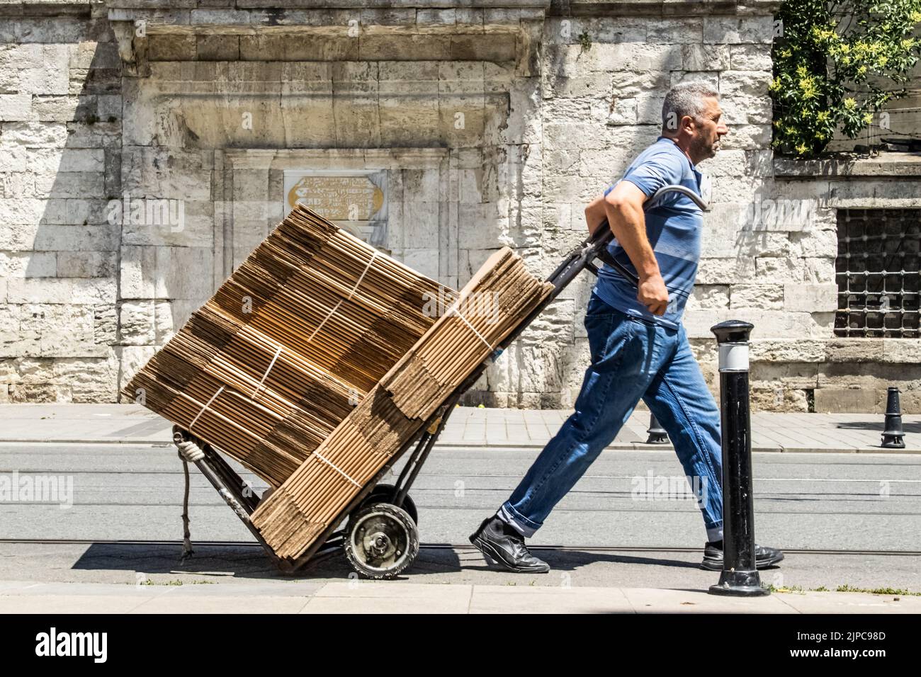 A porter pulls a trolley with a pile of folded cardboard through an ...