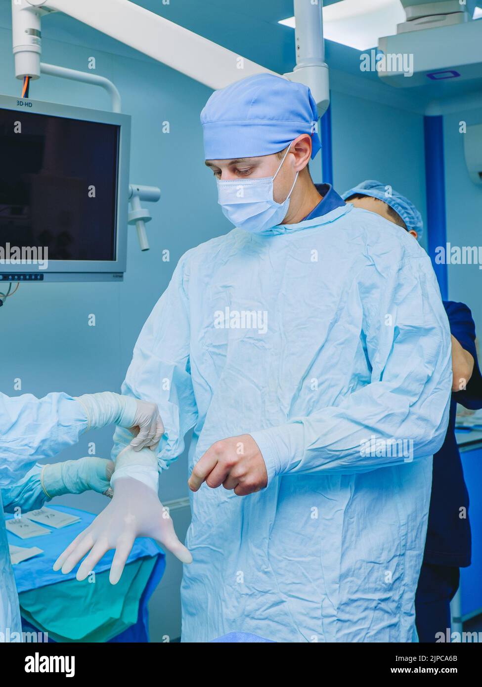 A male surgeon is preparing for an operation. Assistant nurses will ...