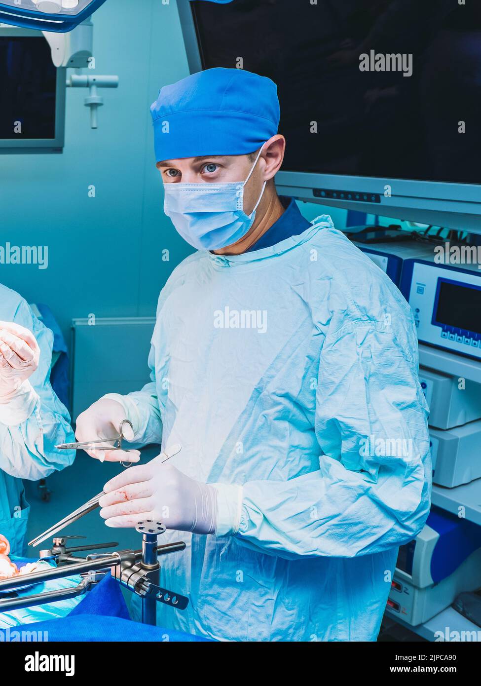 A male surgeon operates on a patient with surgical instruments. A ...