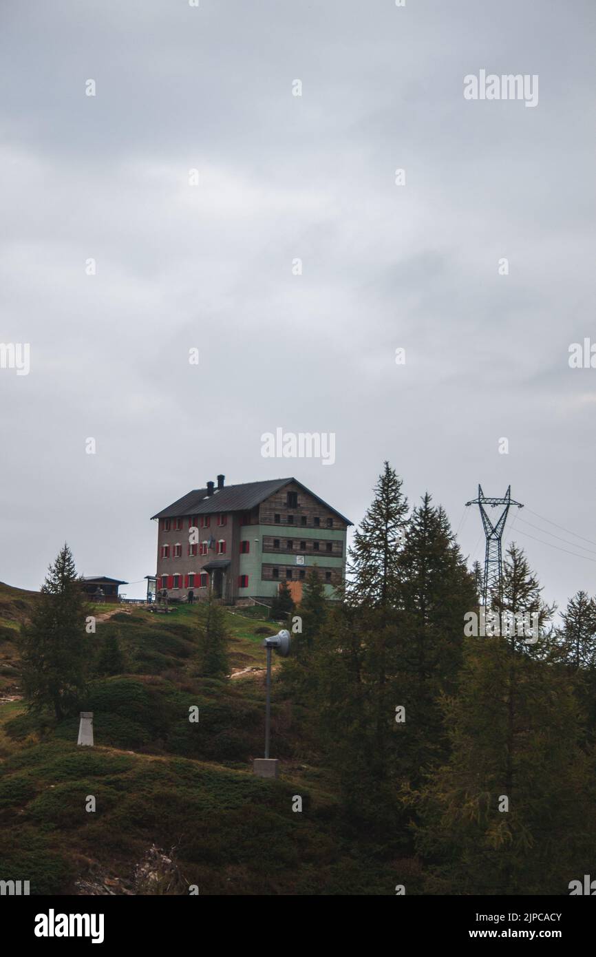 A small house on top of the green hill with clouded sky in the ...