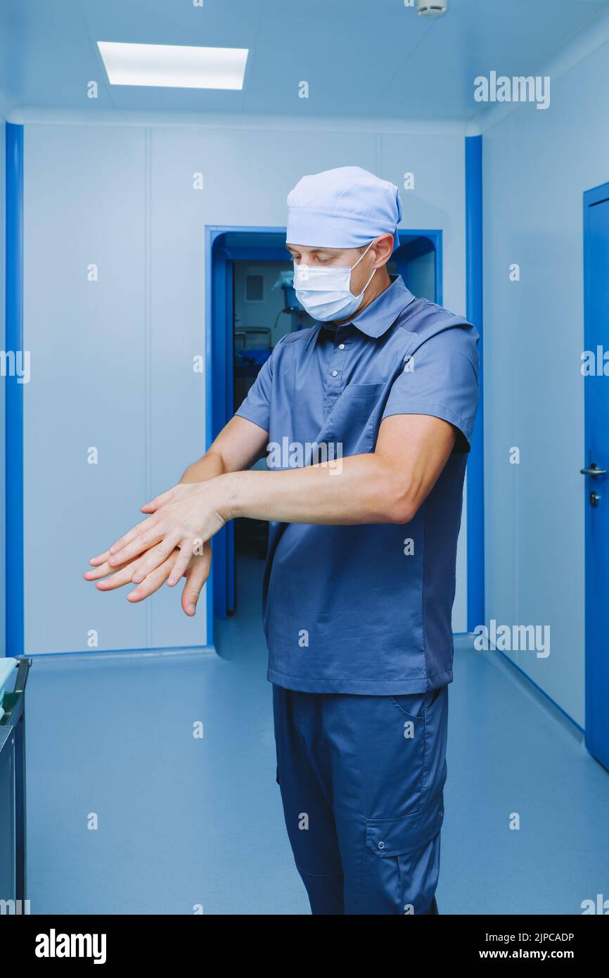 The surgeon treats the hands with a disinfectant composition before ...