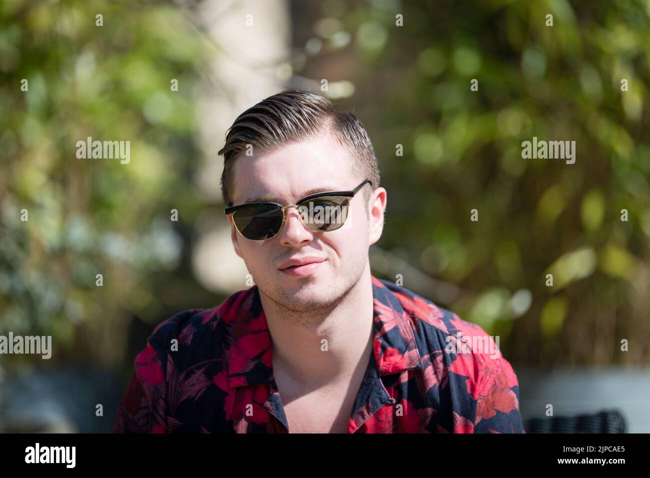 A shallow shot of a caucasian male wearing black glasses with sunlight ...