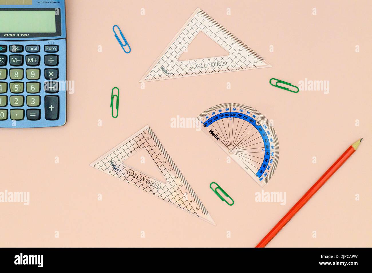 A top view of rules, a calculator, and other school supplies on a pink ...