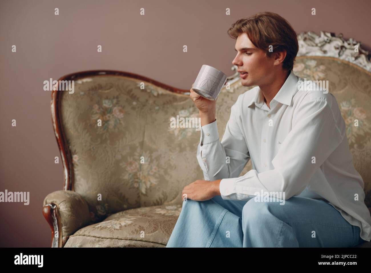 Portrait european young man drinking and enjoying afternoon tea or ...