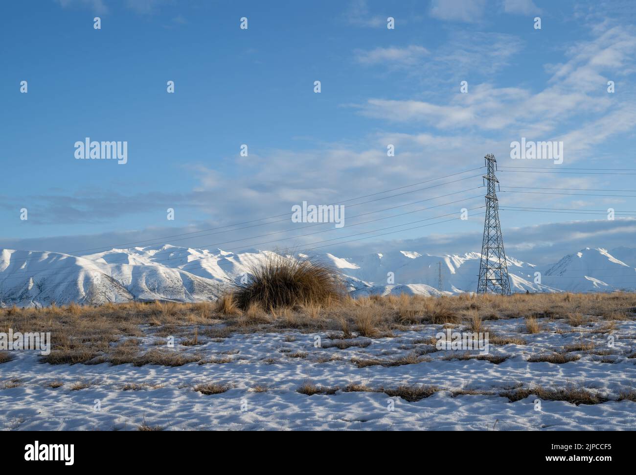 High voltage transmission towers and powerlines with snow-covered Ben Ohau range in the distance ...
