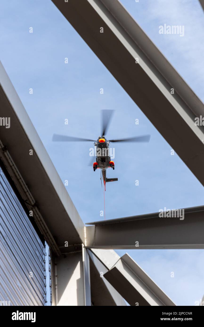A vertical low angle shot of a helicopter flying over the roof of the ...