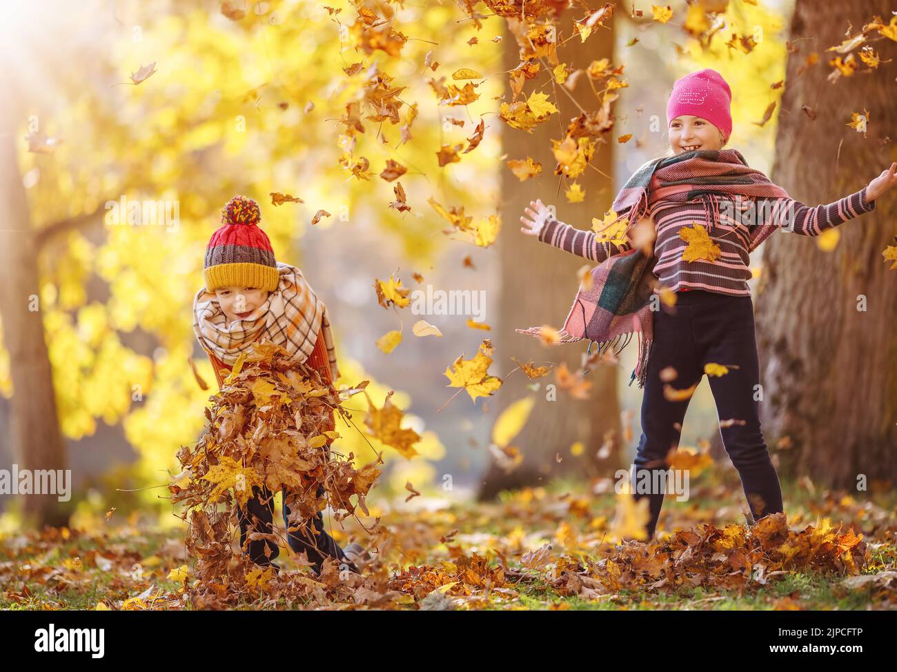 Children throwing colourful leaves in autumnal park Stock Photo - Alamy