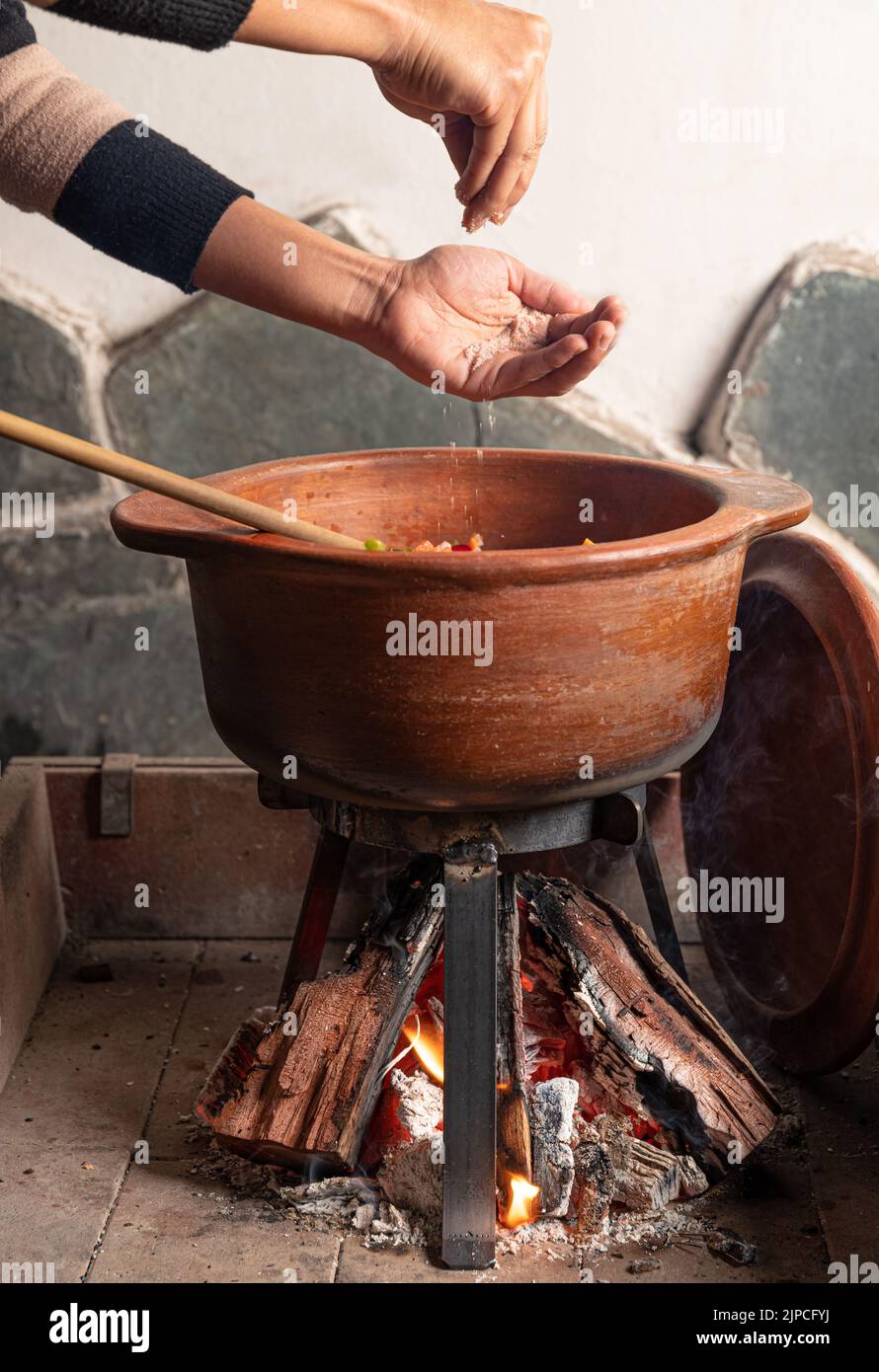 A vertical shot of person adding pepper into a clay pot Stock Photo - Alamy