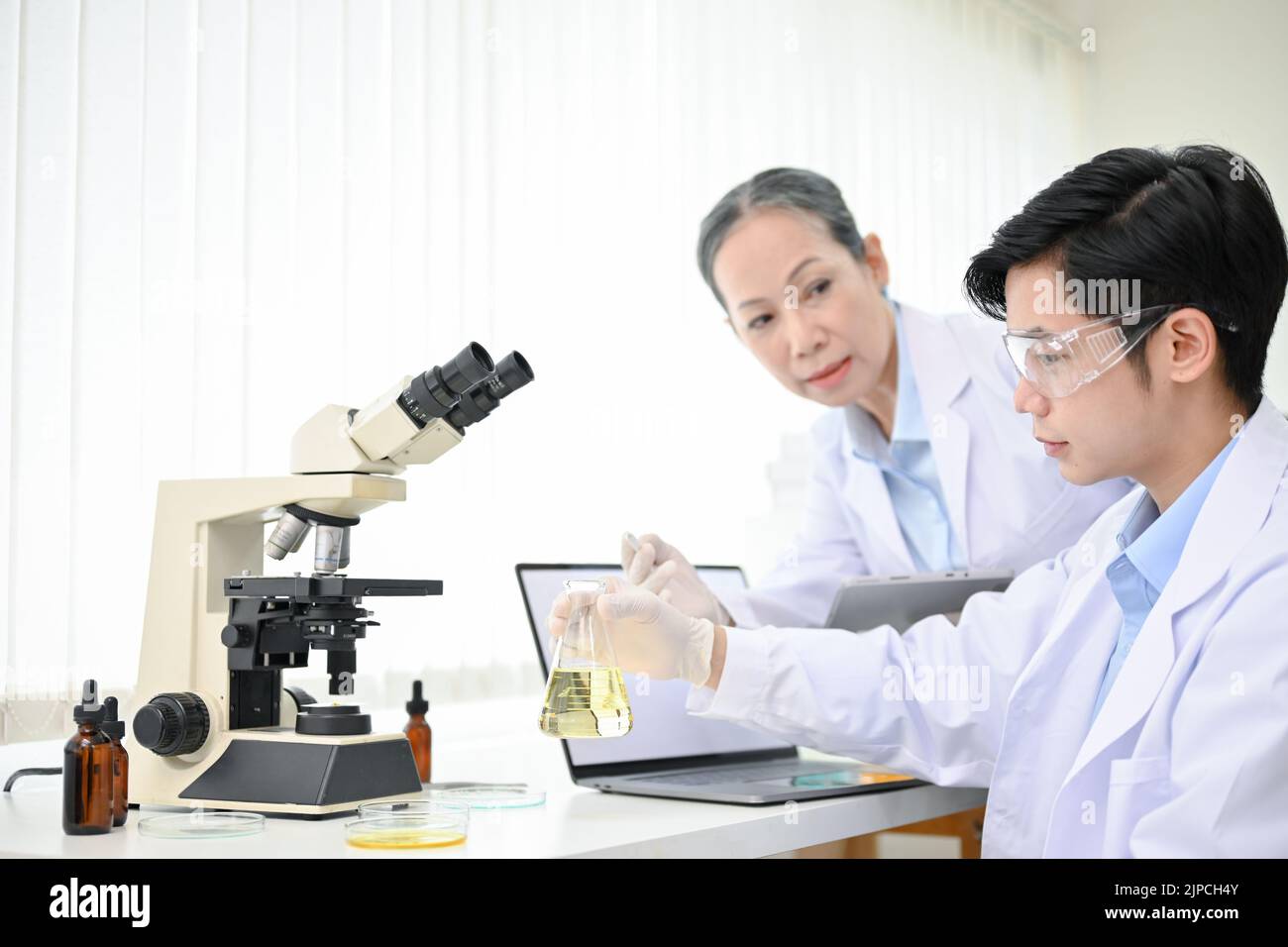 Concentrated and professional millennial Asian male scientist adjust a ...