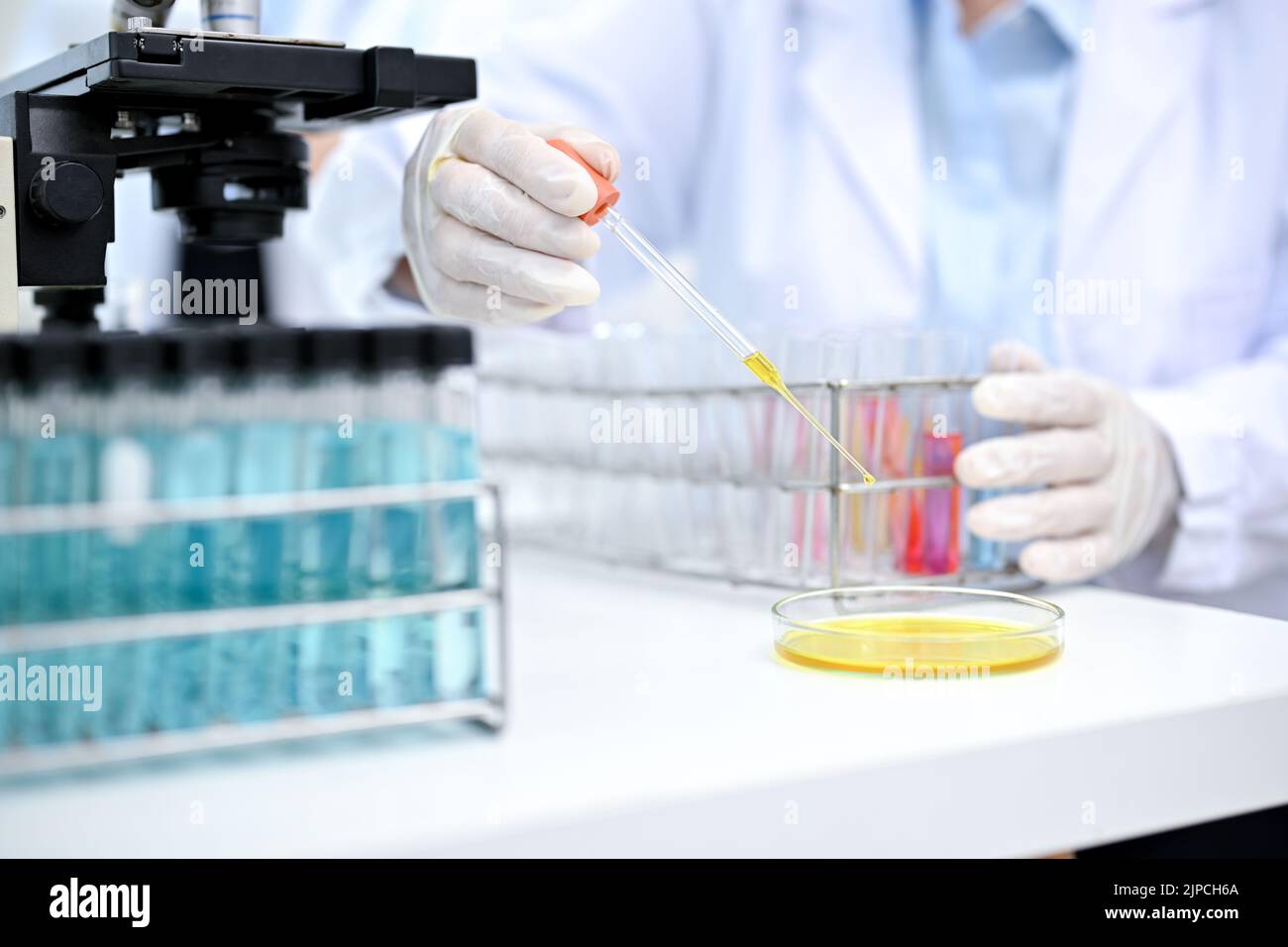 A professional chemist or scientist uses a dropper tube to adjust ...