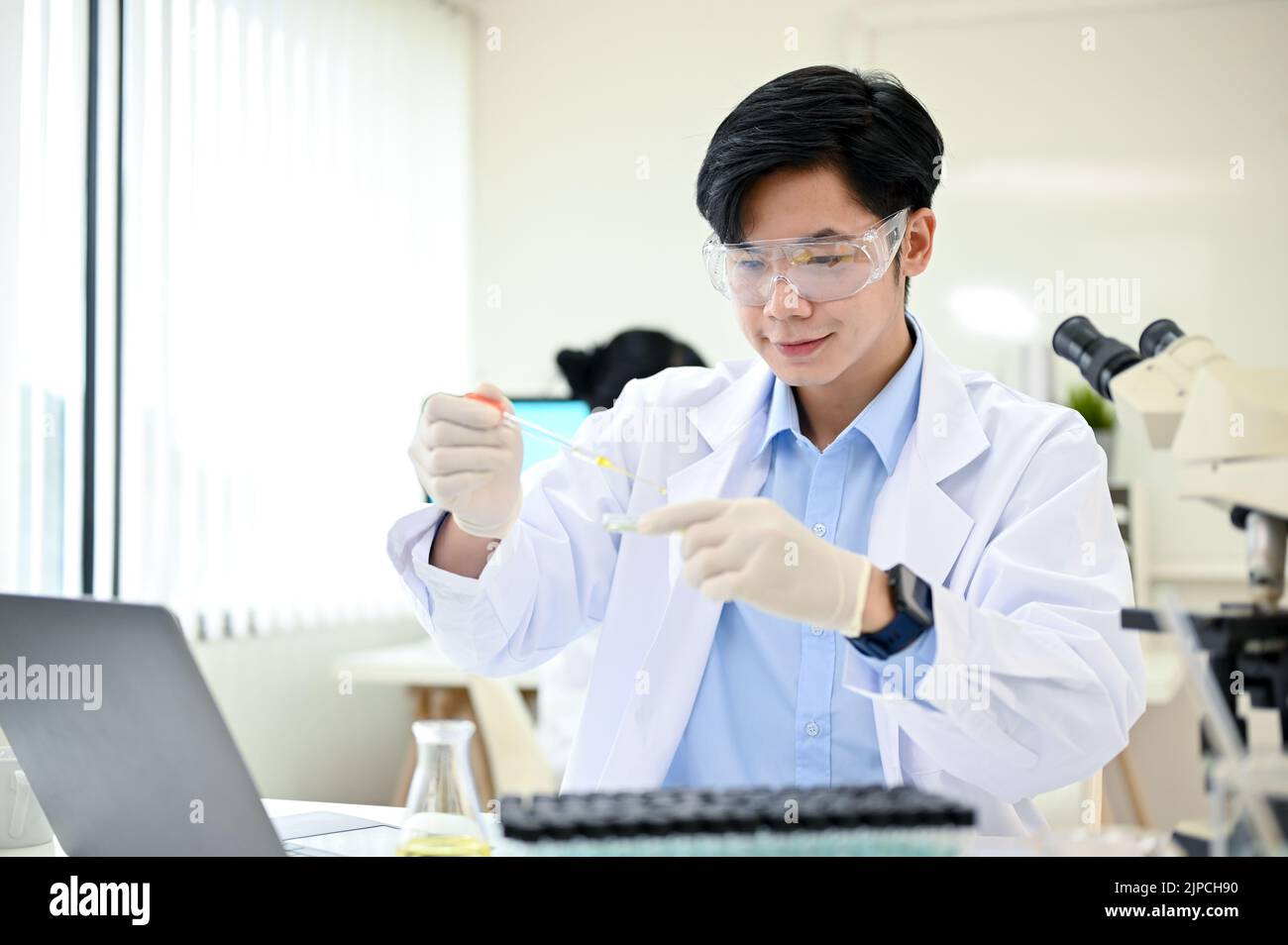 Smart and handsome young Asian male scientist or chemist adjusts a ...