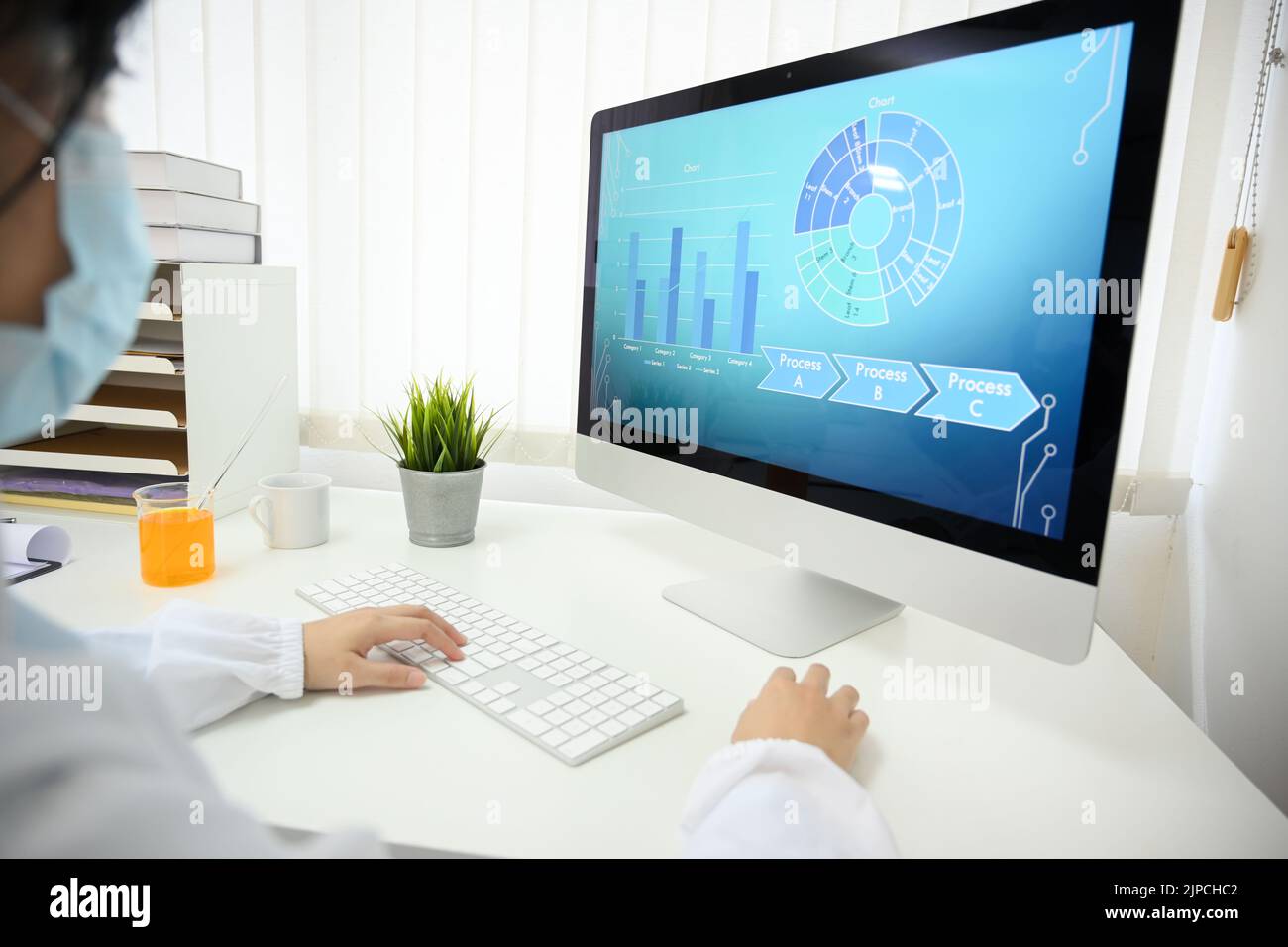 A male scientist working at his office desk looking at his desktop ...