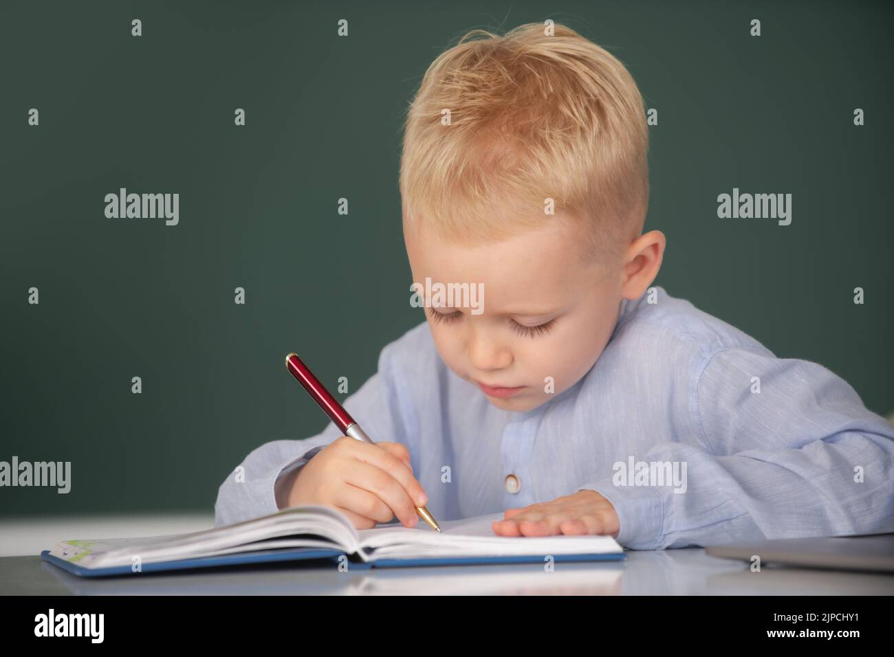 Little schoolboy study in a classroom at elementary school. Kid writing ...