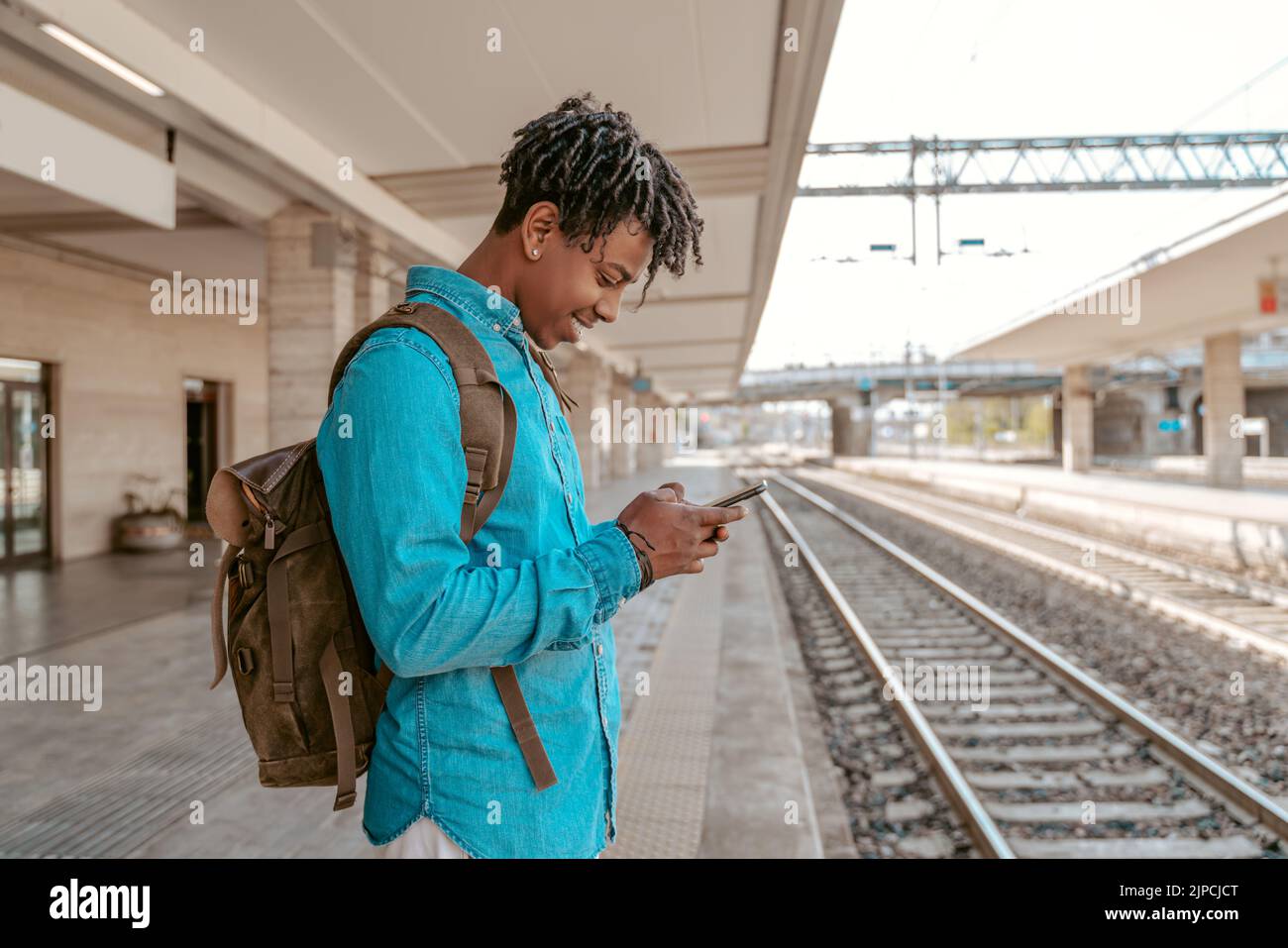 Guy looking at smartphone standing sideways to camera Stock Photo - Alamy