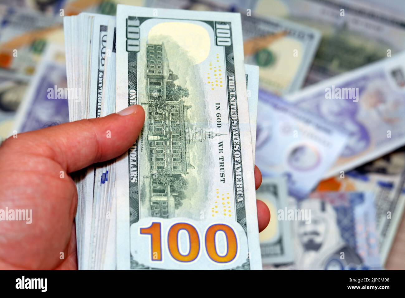 A hand holds a stack of 100 $ one hundred dollars American cash money ...