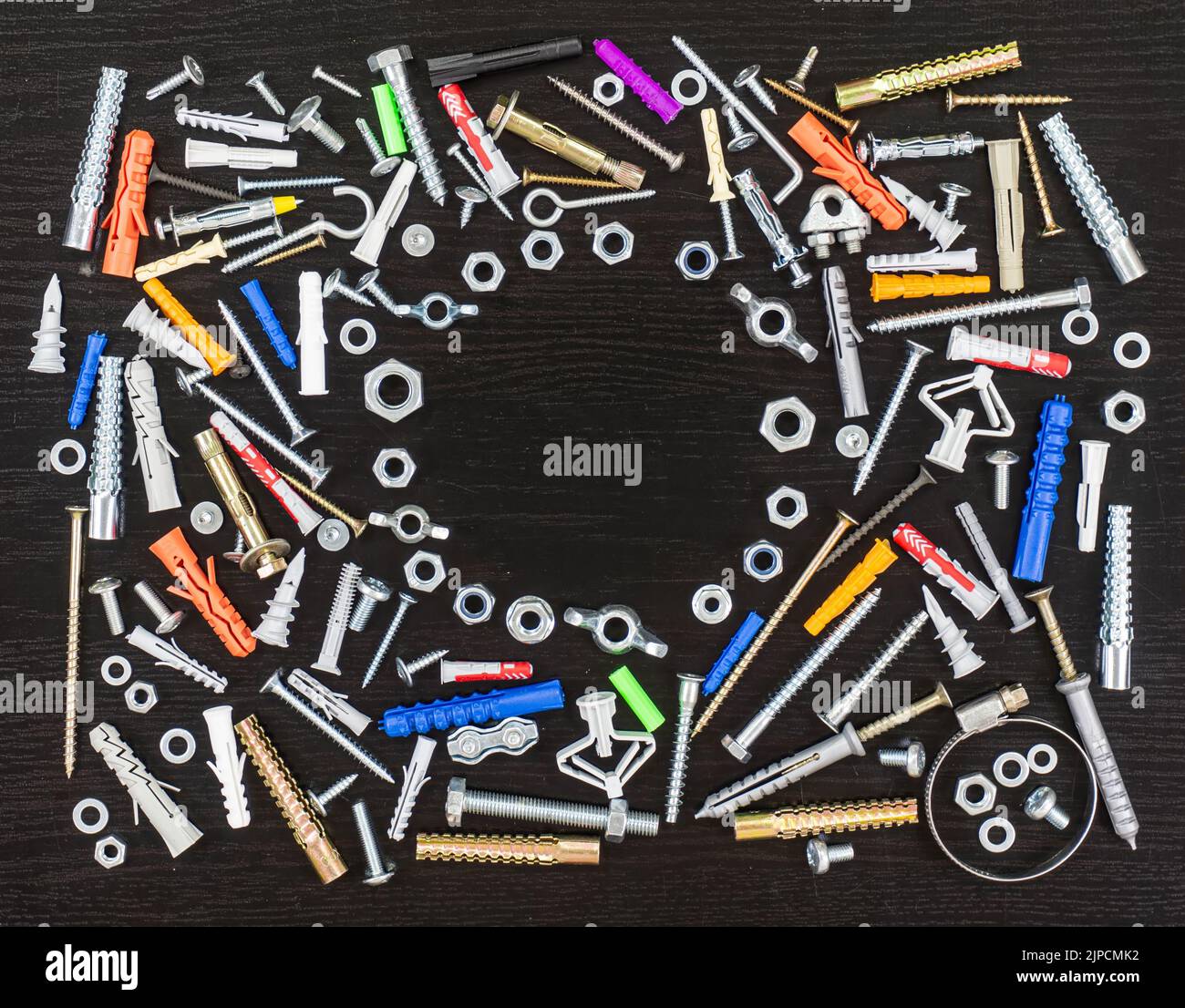 Different types of fasteners on a dark wood background. View from above ...