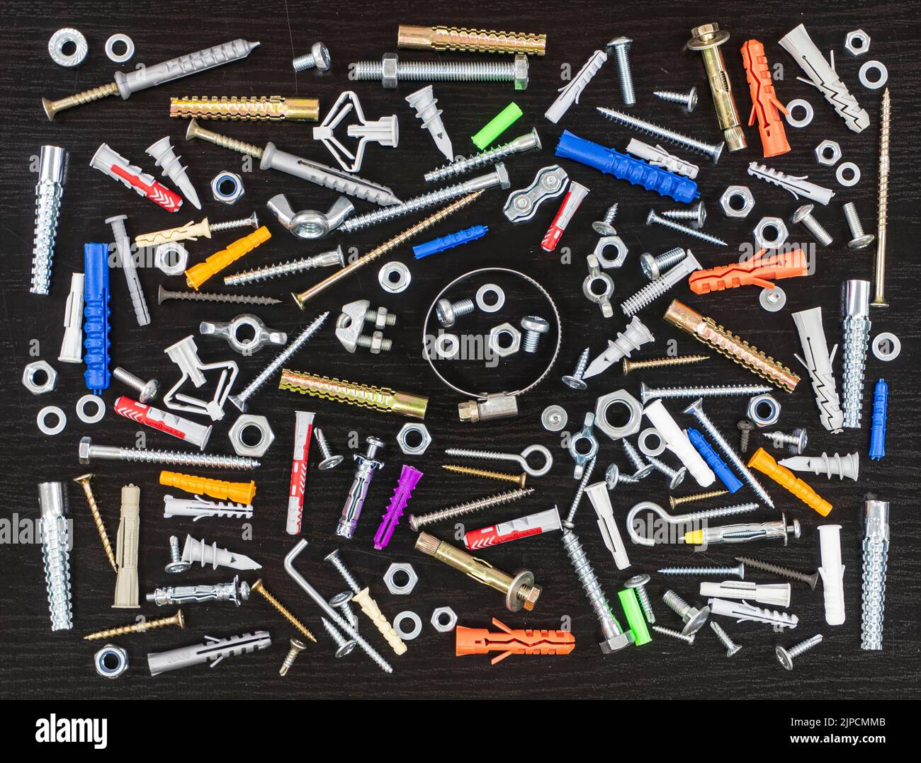 Different types of fasteners on a dark wood background. View from above ...
