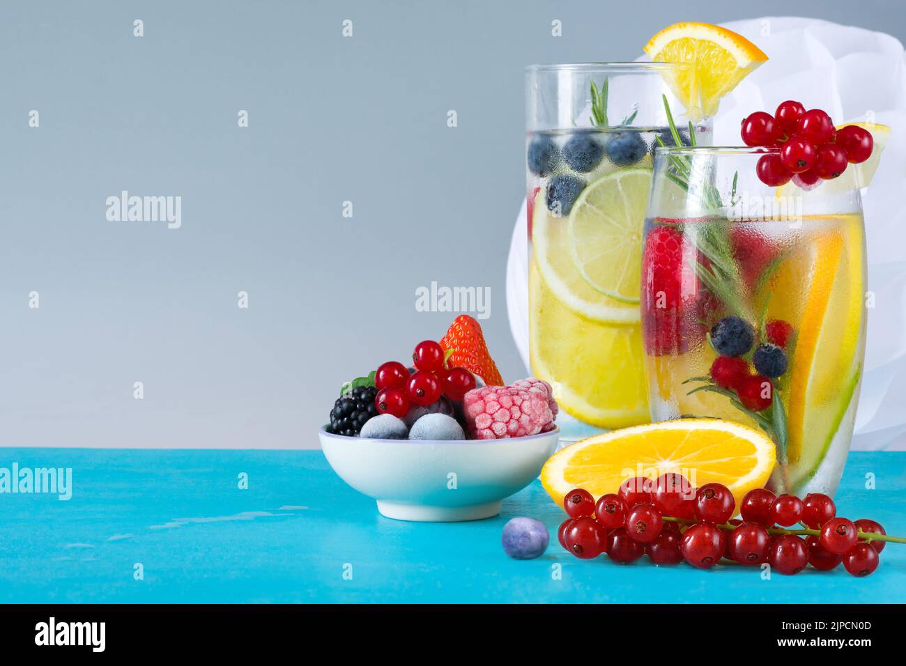 Gray background with frozen berries, citrus drinks in glass glasses ...