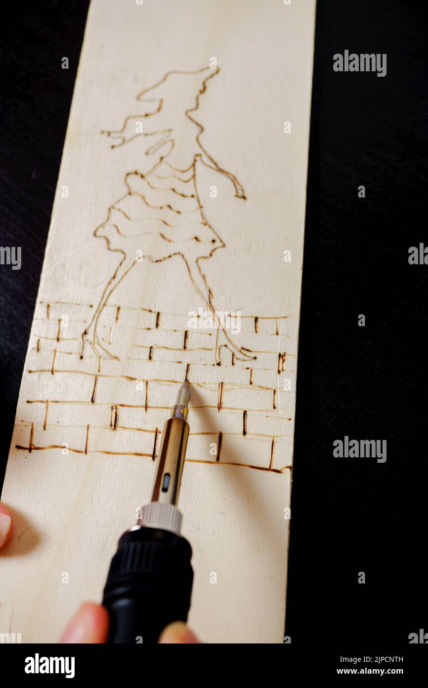 close-up of a wooden board with a pyrographed drawing on a black ...